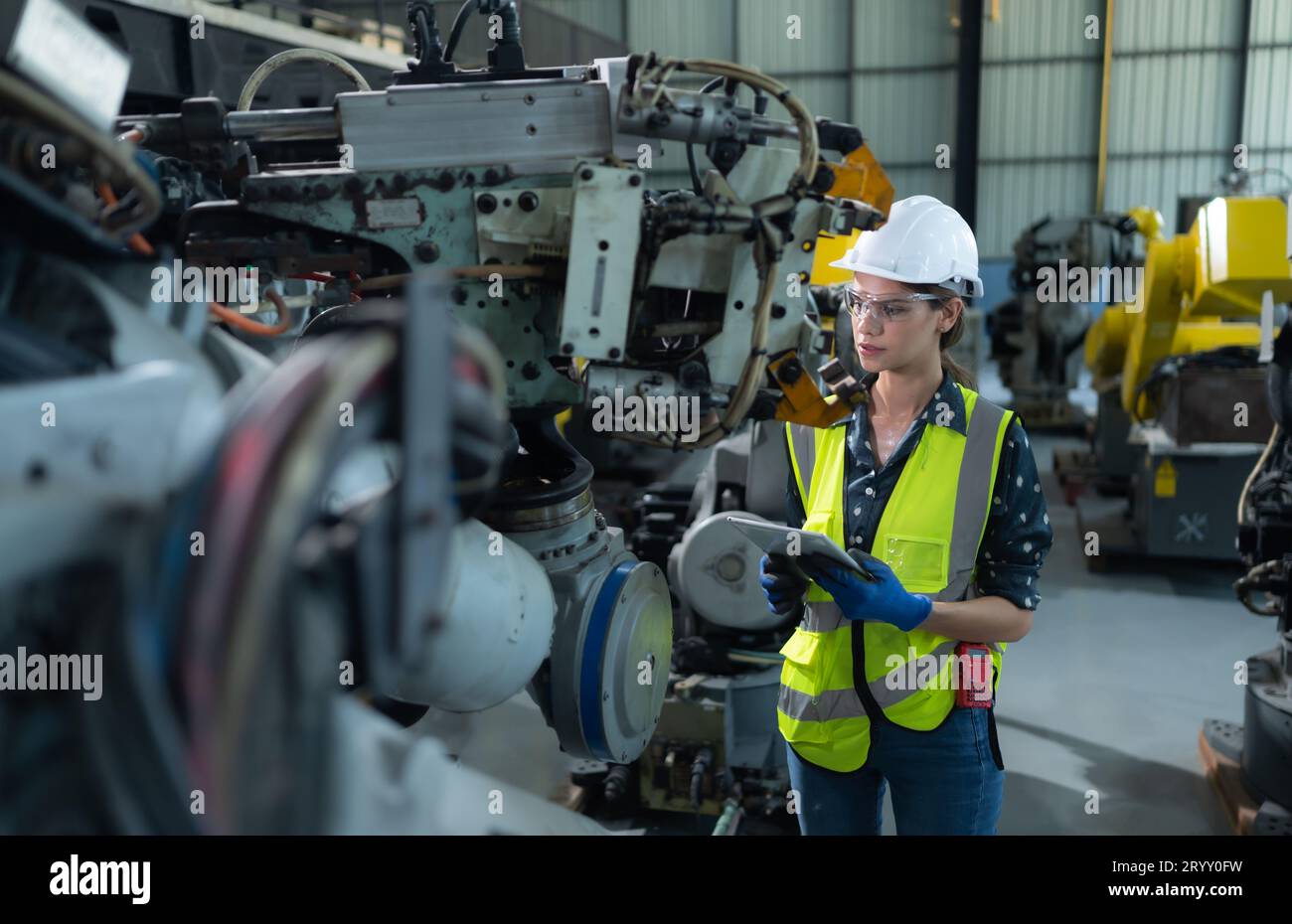 A female engineer installs a program on a robotics arm in a robot ...