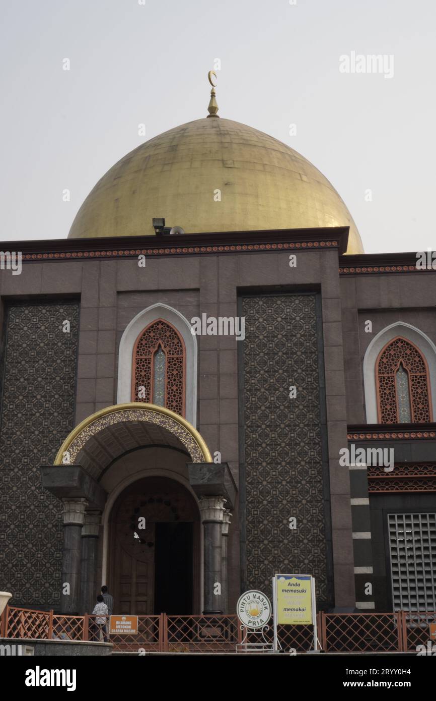 The mosque building with a golden yellow dome appears under a clear sky ...