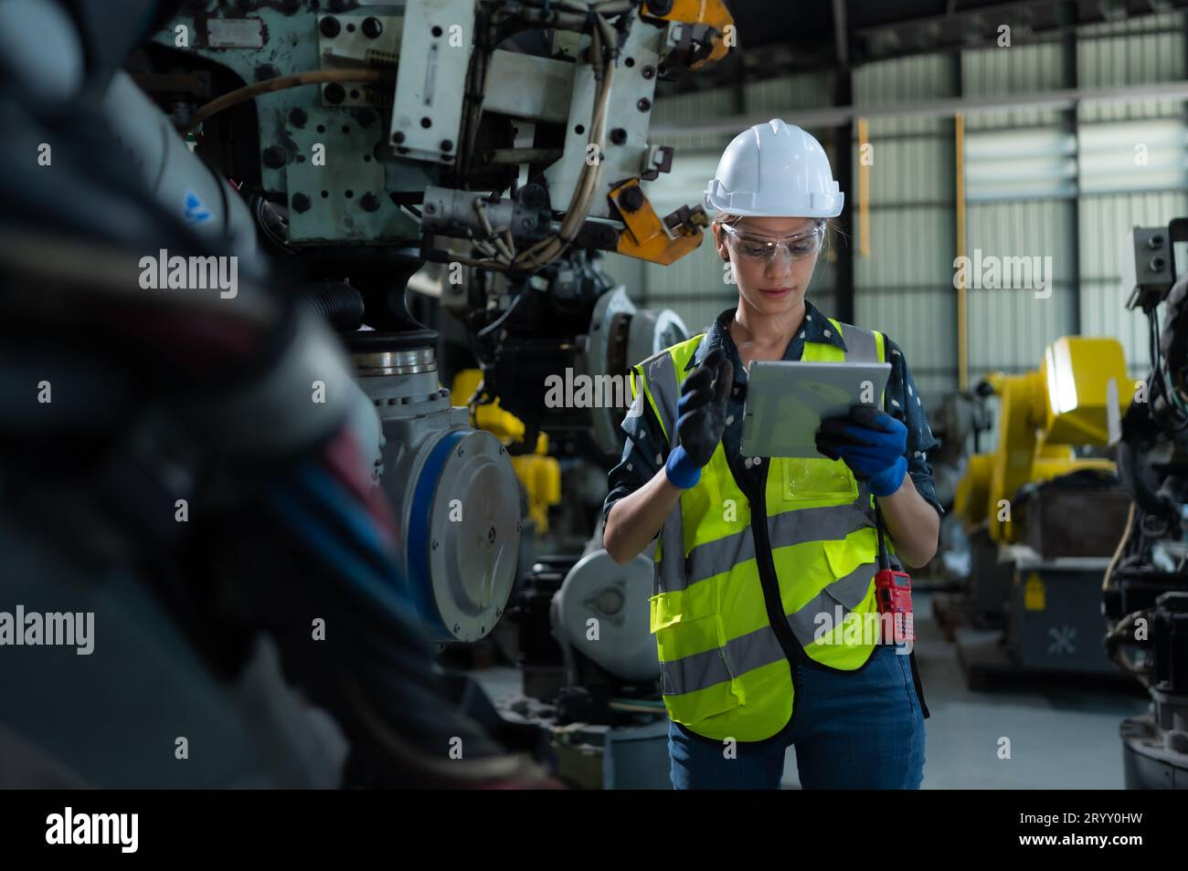 A female engineer installs a program on a robotics arm in a robot ...