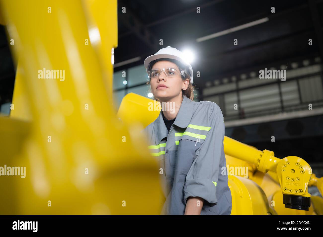 A female engineer installs a program on a robotics arm in a robot ...