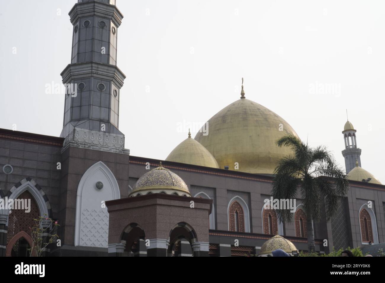The mosque building with a golden yellow dome appears under a clear sky ...
