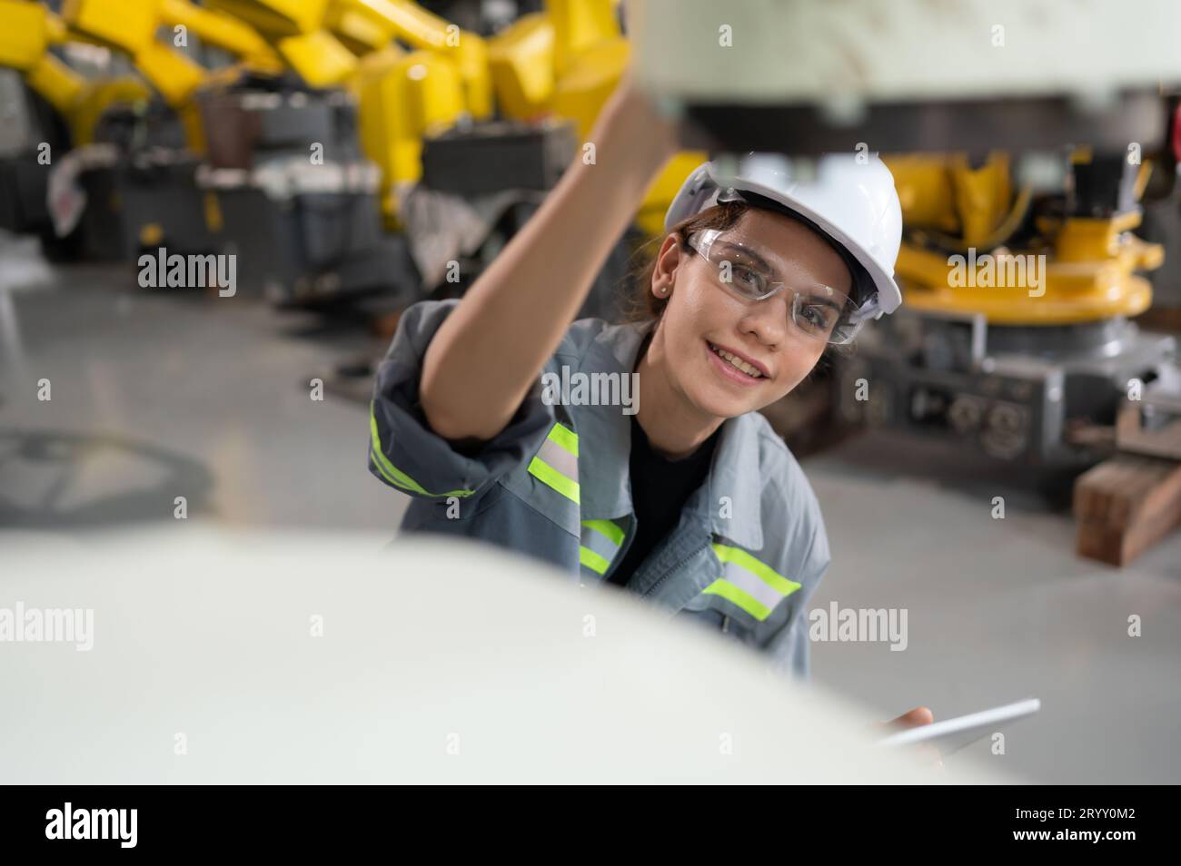 A female engineer installs a program on a robotics arm in a robot ...