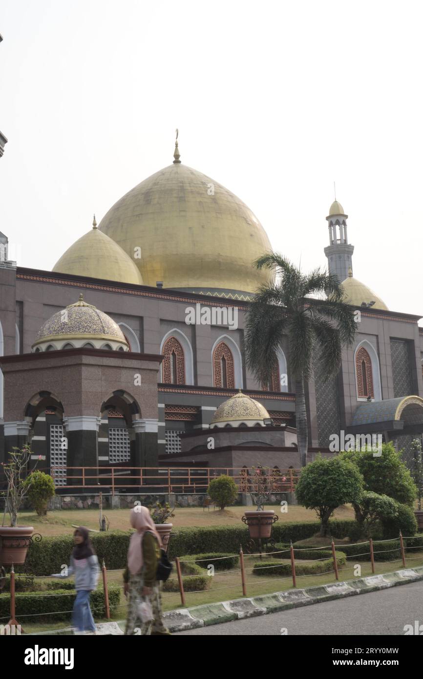 The mosque building with a golden yellow dome appears under a clear sky ...
