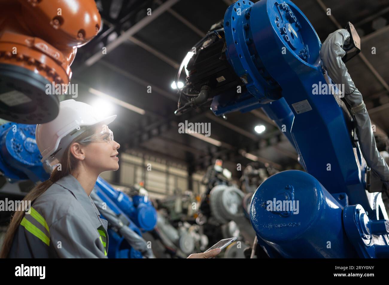 A female engineer installs a program on a robotics arm in a robot ...