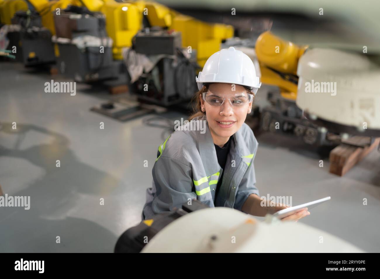 A female engineer installs a program on a robotics arm in a robot ...