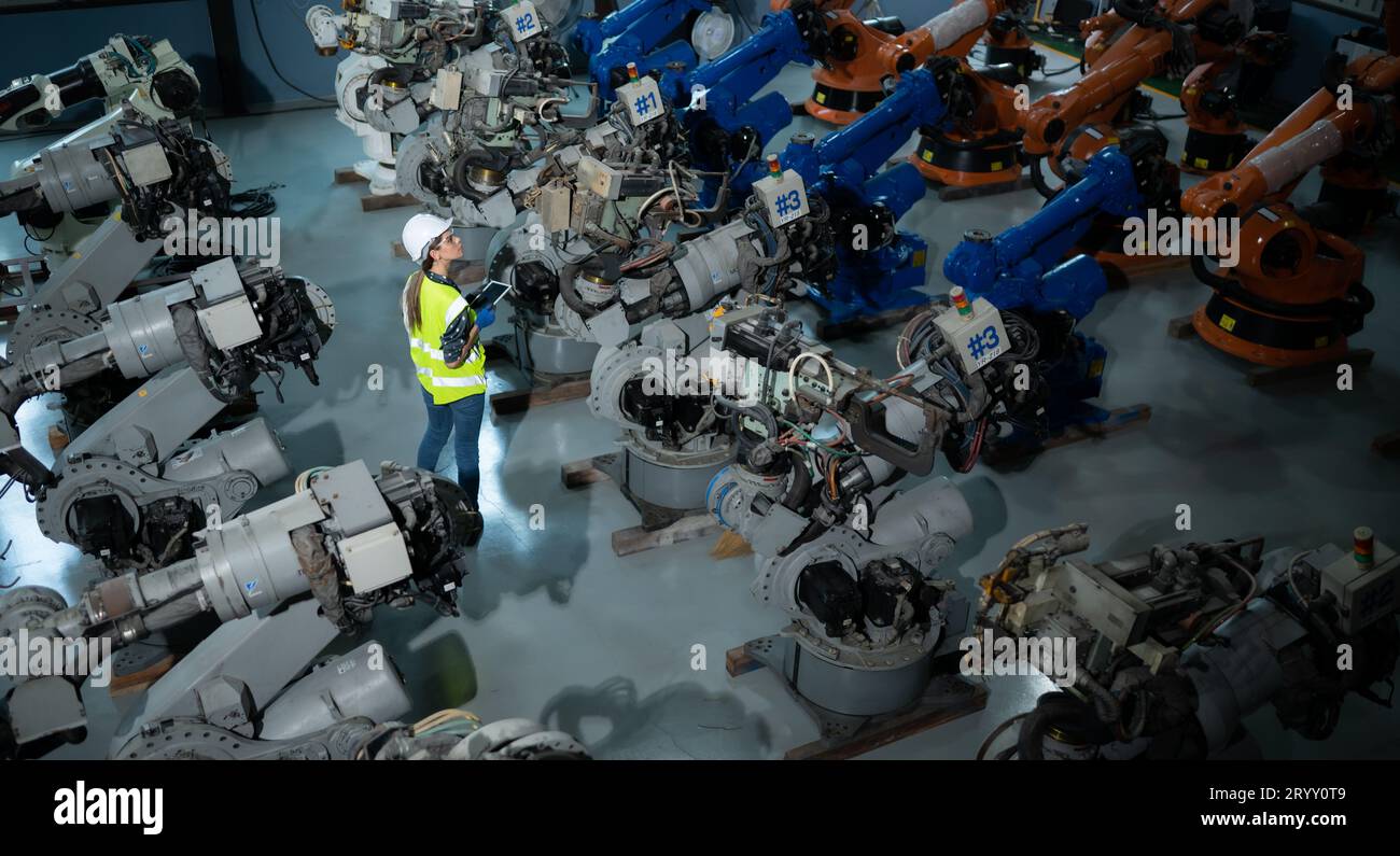 A female engineer installs a program on a robotics arm in a robot ...