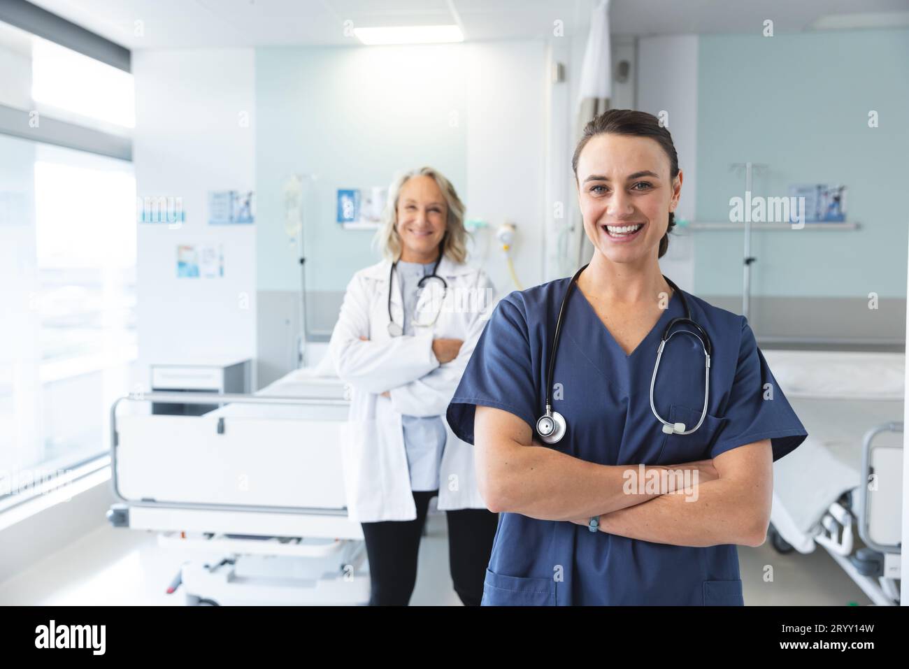 Portrait of happy caucasian female doctors wearing scrubs and lab coat ...