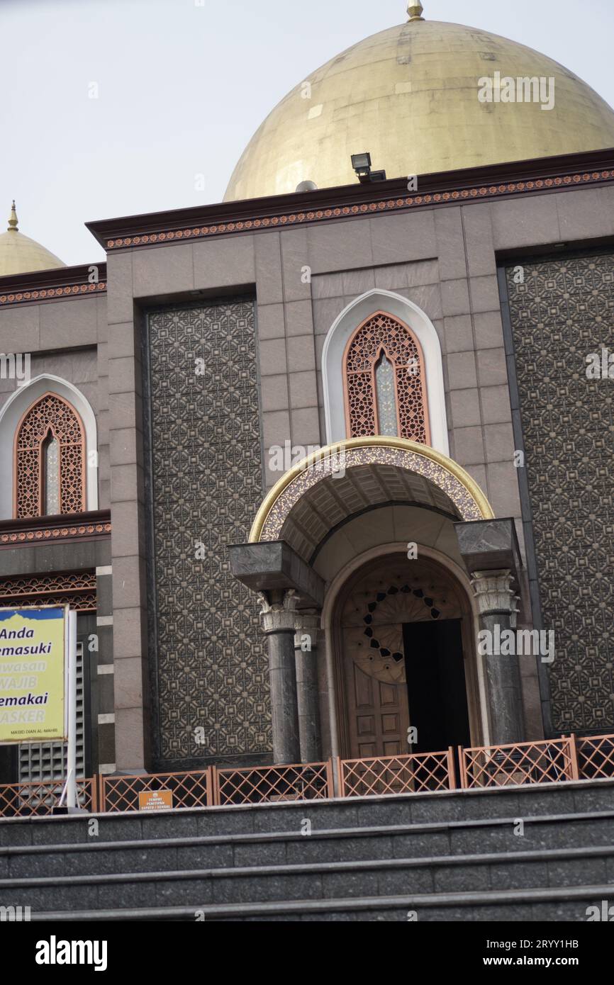 The mosque building with a golden yellow dome appears under a clear sky ...