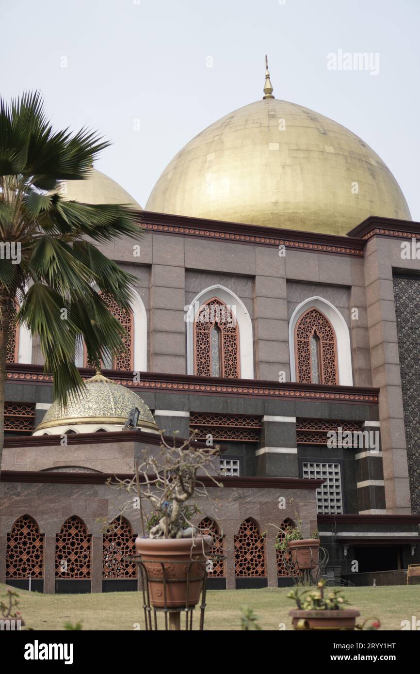 The mosque building with a golden yellow dome appears under a clear sky ...