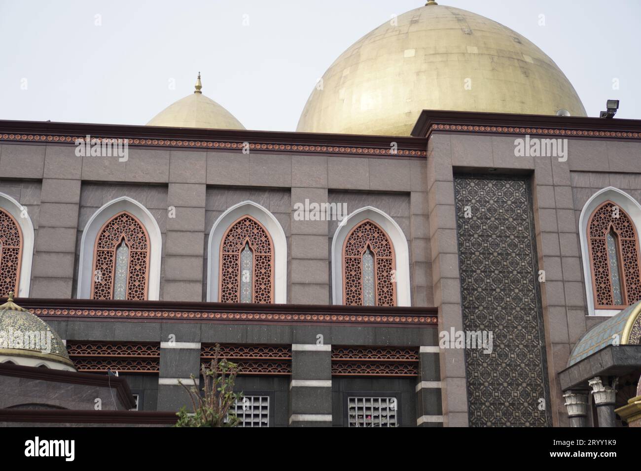 The mosque building with a golden yellow dome appears under a clear sky ...