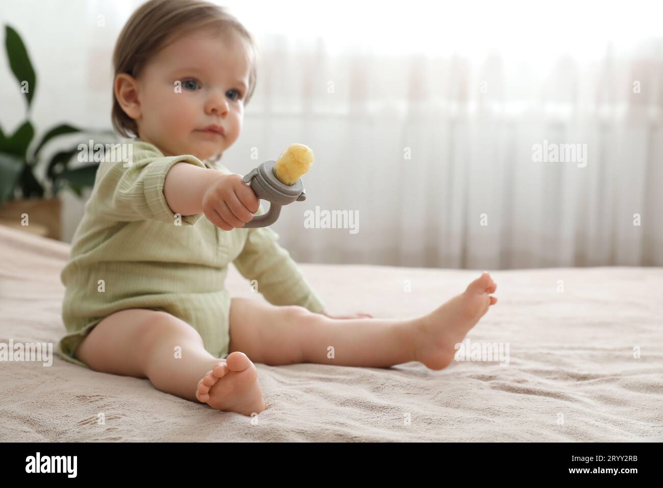 Cute baby girl with nibbler on bed at home. Space for text Stock Photo ...