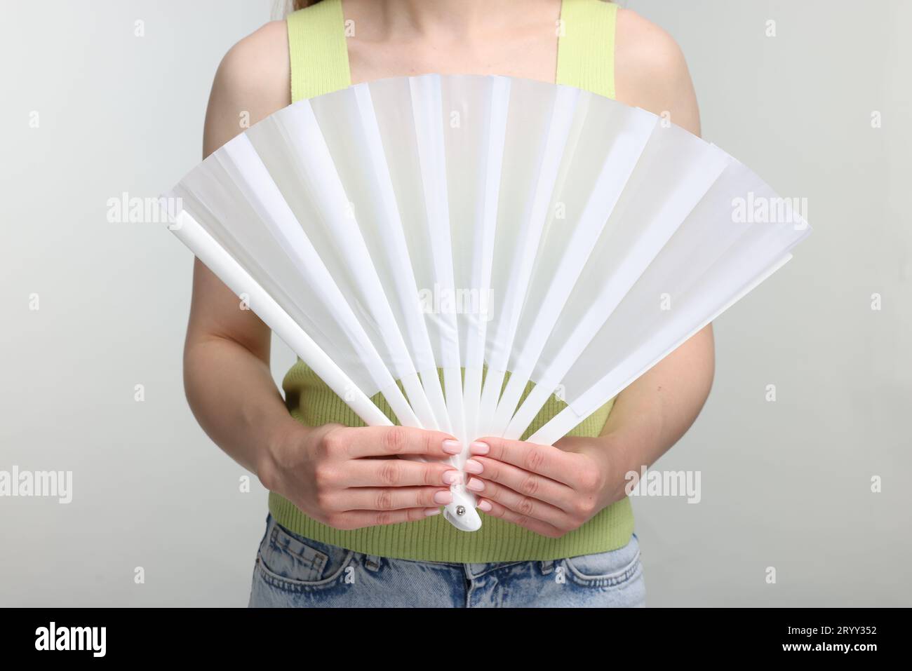 Woman with white hand fan on light grey background, closeup Stock Photo ...