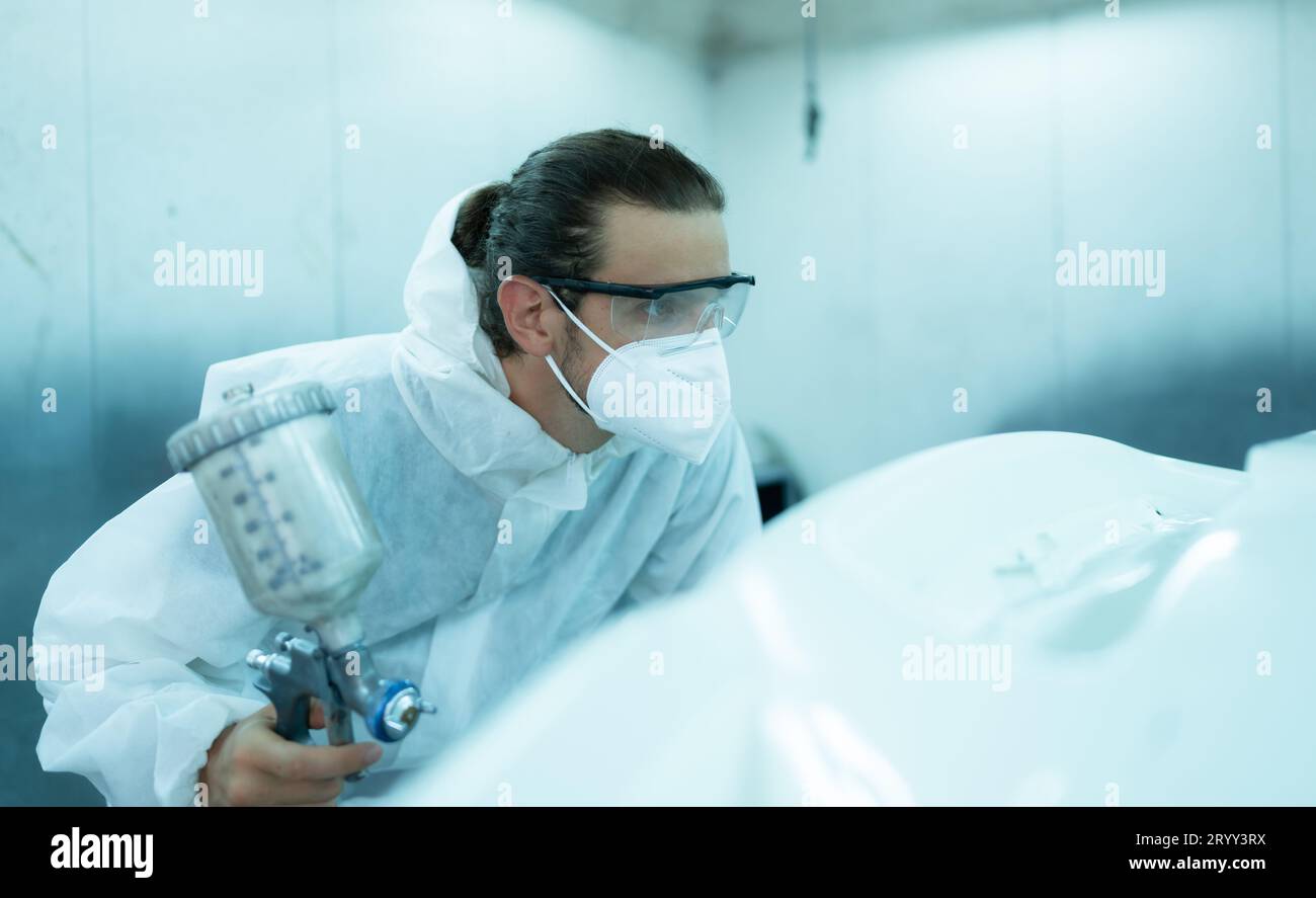 Auto mechanic in car spray room Inspecting the paint sprayed into the ...