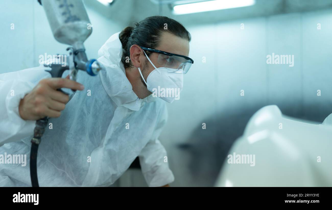 Auto mechanic in car spray room Inspecting the paint sprayed into the ...