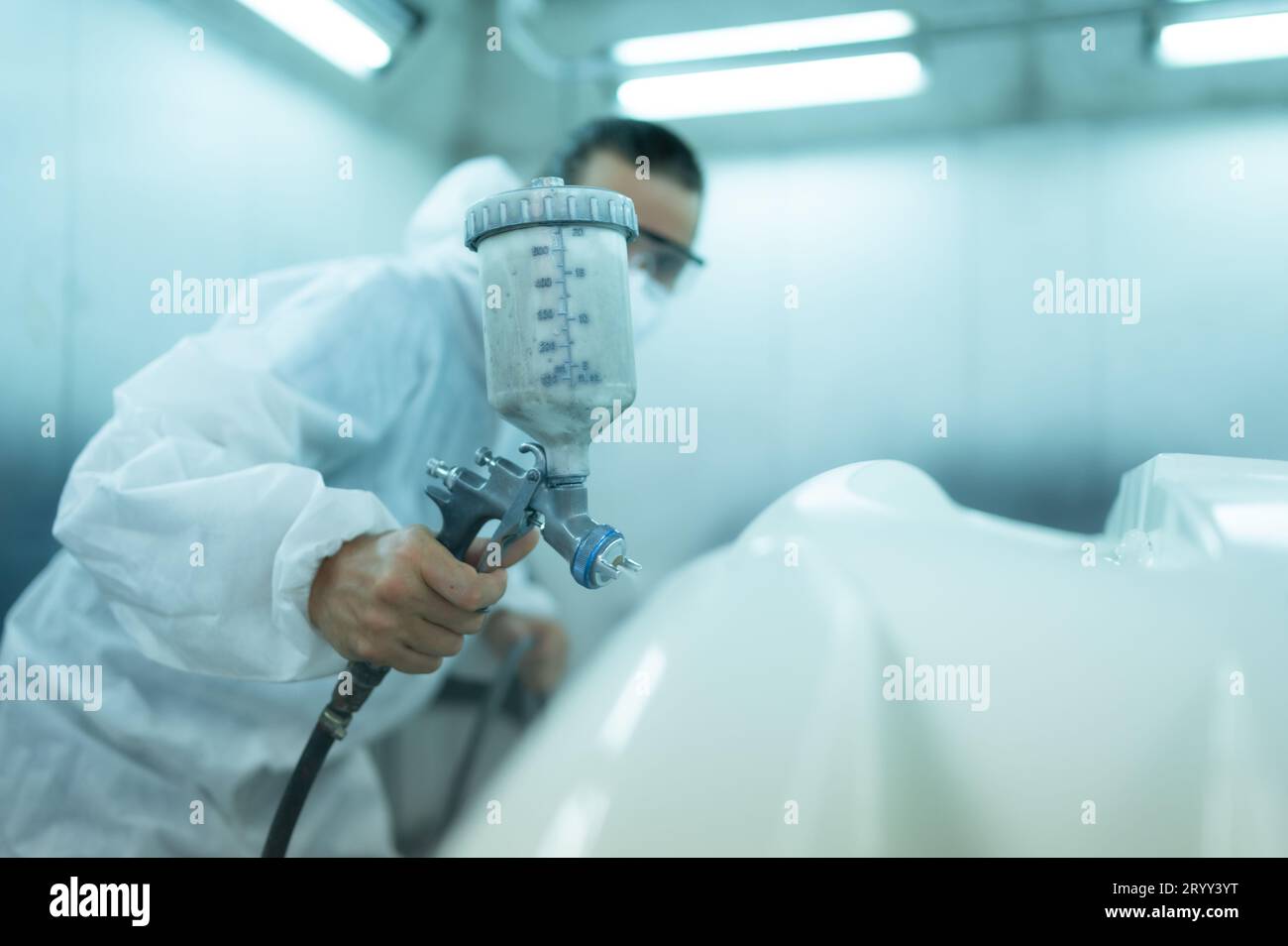 Auto mechanic in car spray room giving the spray nozzle injected into ...