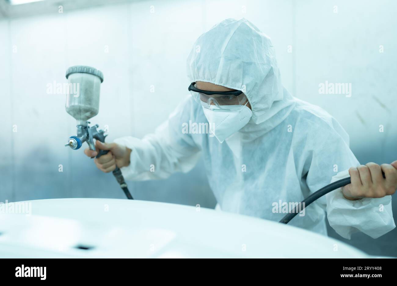 Auto mechanic in car spray room giving the spray nozzle injected into ...