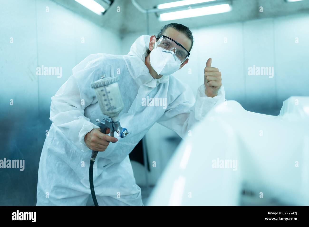 Auto mechanic in car spray room Inspecting the paint sprayed into the ...
