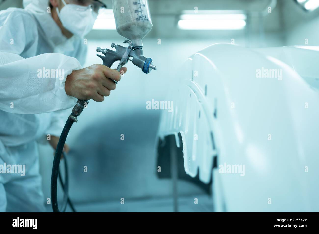 Auto mechanic in car spray room giving the spray nozzle injected into ...