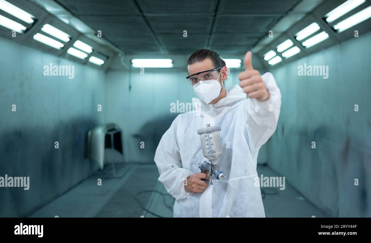Auto mechanic in car spray room Inspecting the paint sprayed into the ...