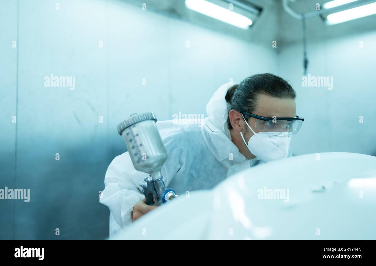 Auto mechanic in car spray room Inspecting the paint sprayed into the ...