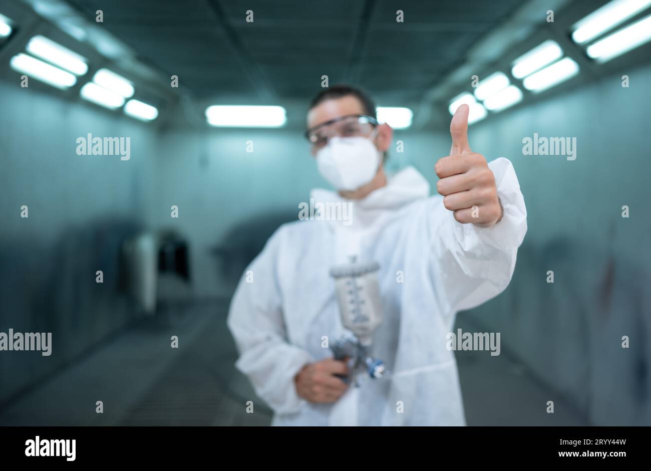 Auto mechanic in car spray room Inspecting the paint sprayed into the ...