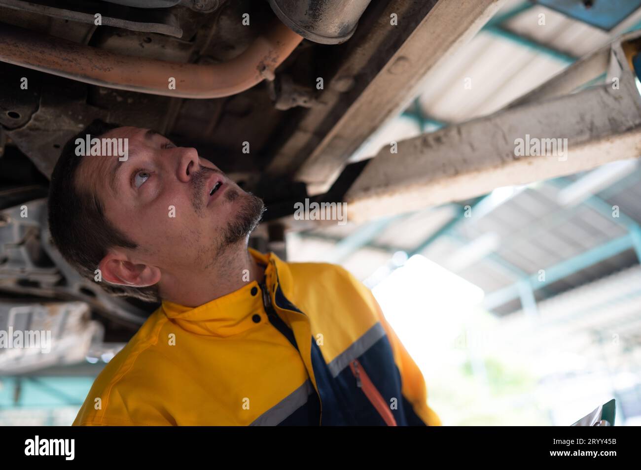 Auto repair mechanic the undercarriage of the car is being inspected ...