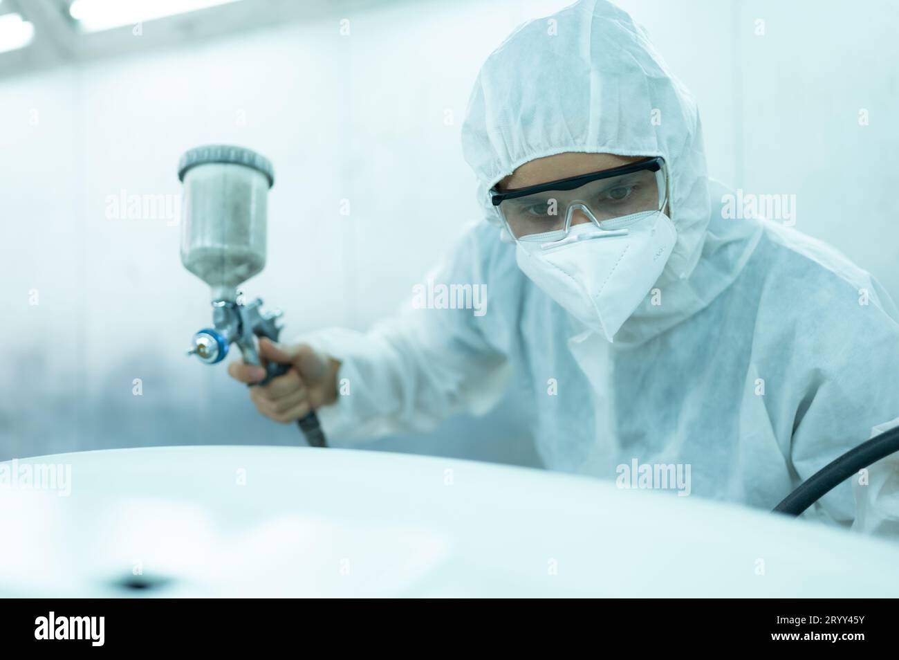 Auto mechanic in car spray room Inspecting the paint sprayed into the ...