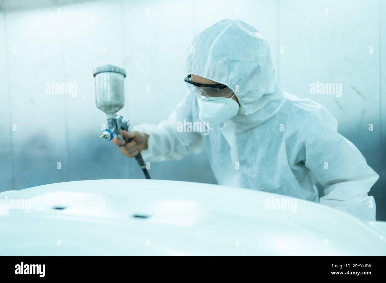 Auto mechanic in car spray room giving the spray nozzle injected into ...