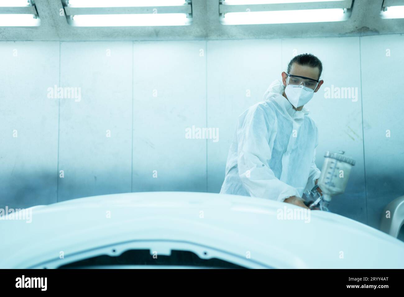 Auto mechanic in car spray room giving the spray nozzle injected into ...