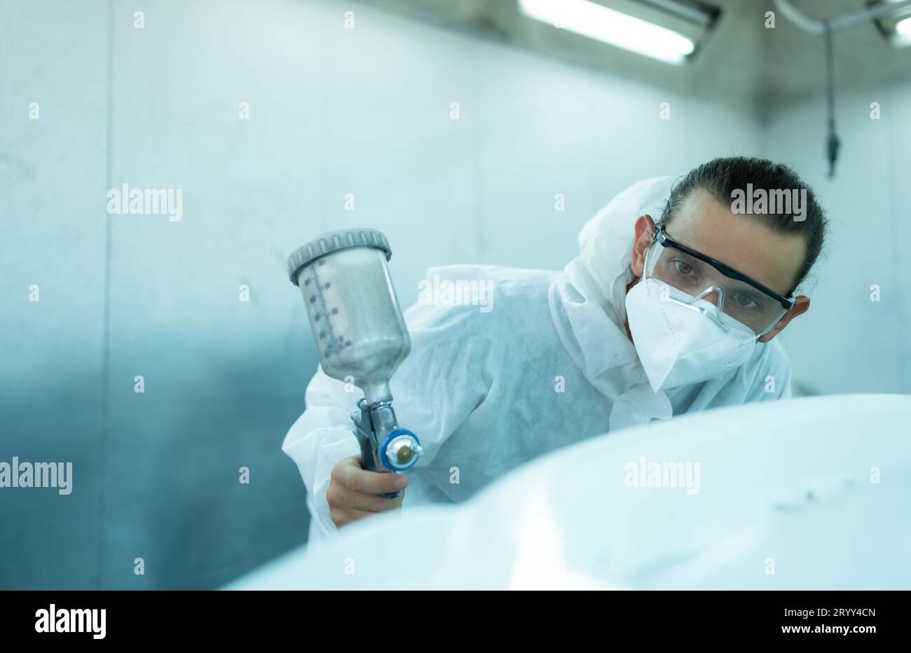 Auto mechanic in car spray room Inspecting the paint sprayed into the ...