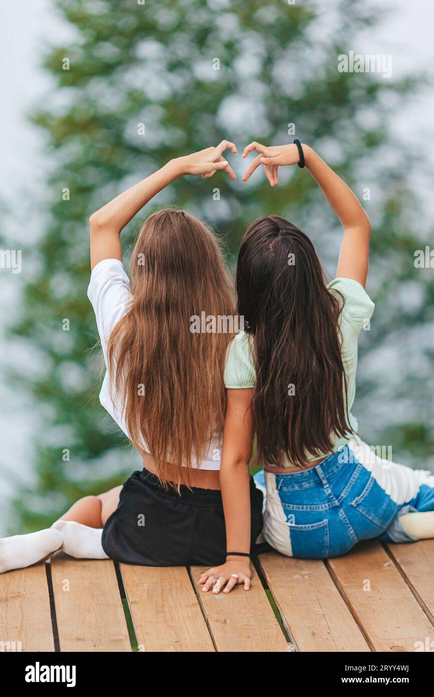 Back view of young girls sit on a terrace at a height in the mountains ...