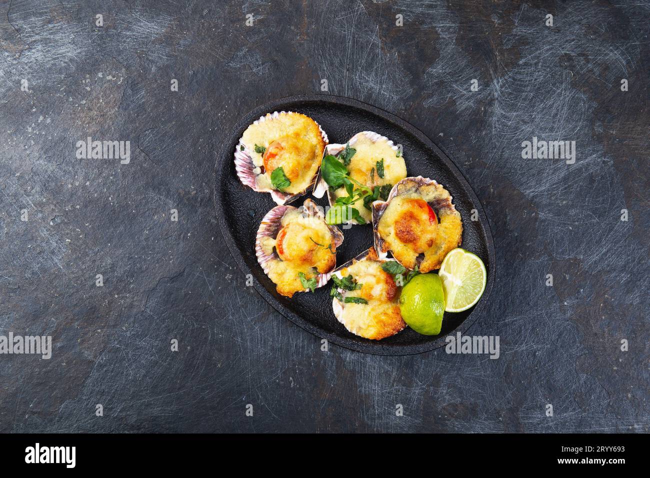 Baked seafood shellfish scallops with cheese and lemon. black ...