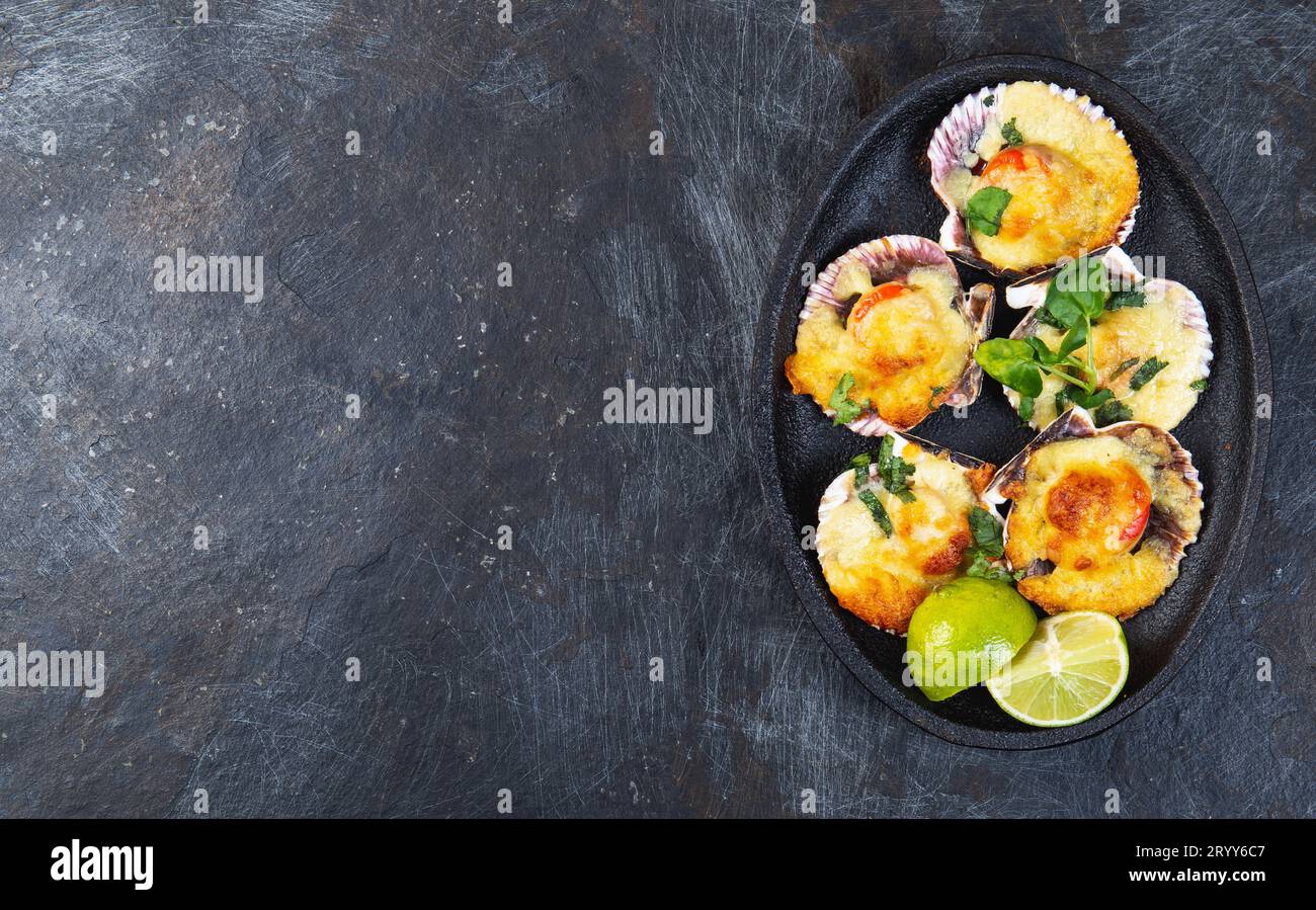 Baked seafood shellfish scallops with cheese and lemon. black ...
