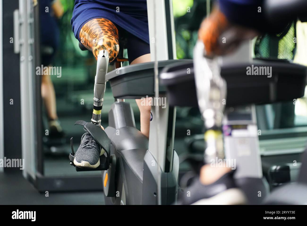 Young female with one prosthetic leg with exercising with a spinning ...