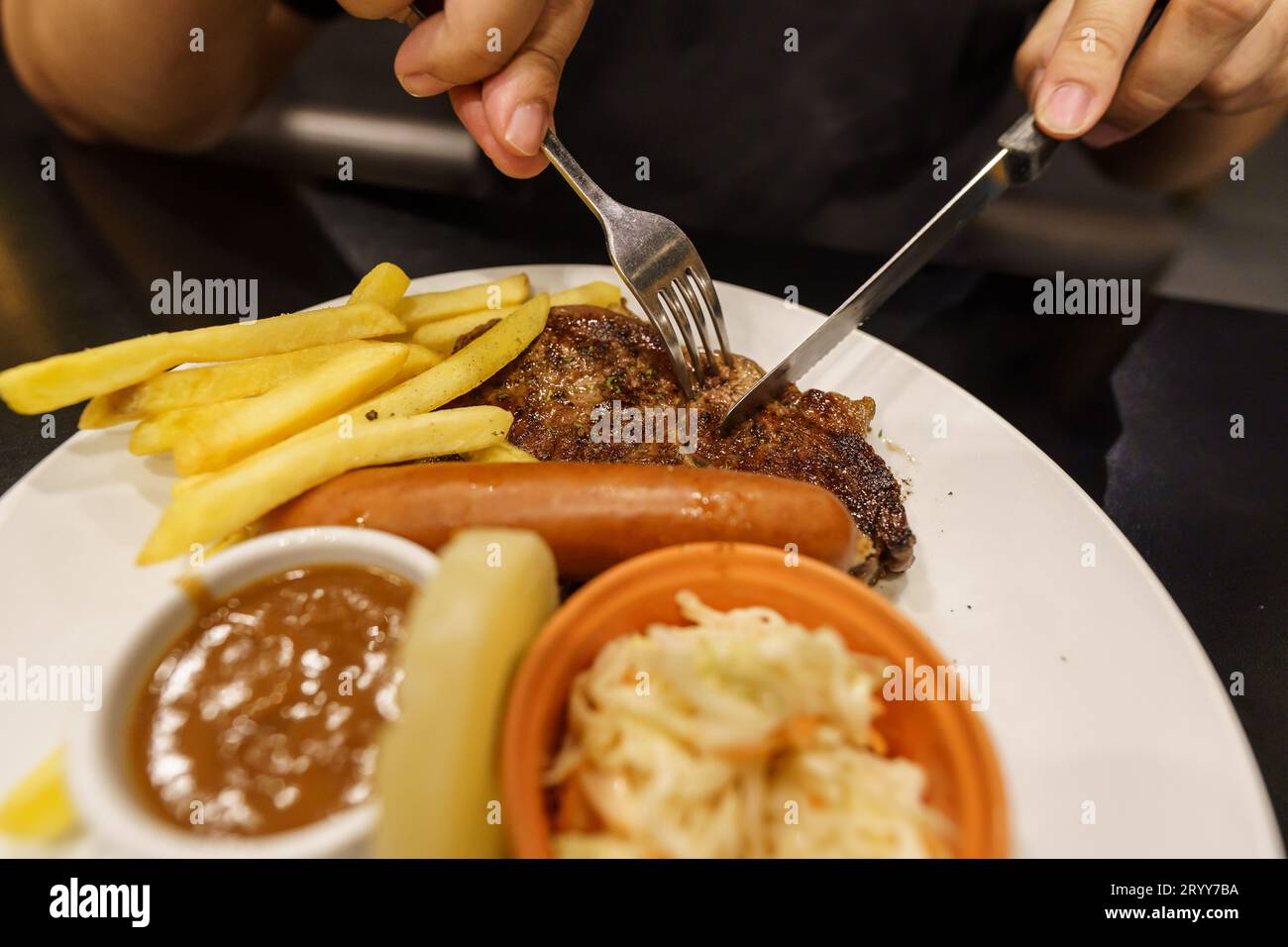 Man eating Grilled Meats stake from plate. hand holding knife and fork ...