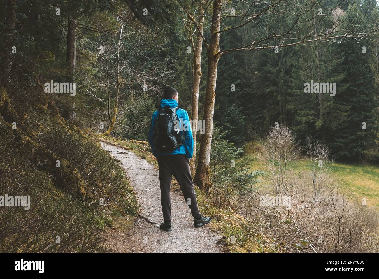 A guy tourist with a backpack stands on a mountain trail and looks into ...