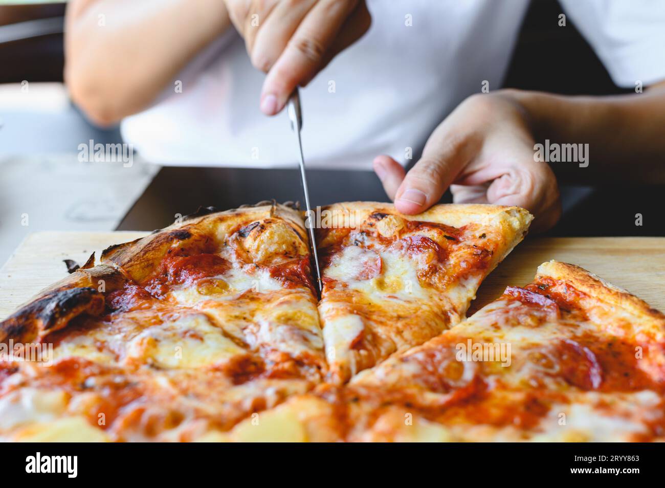 Wood fire cheesy pizza slice in hand. Traditional Hawaiian and Salami pizza savory dish flavour ...