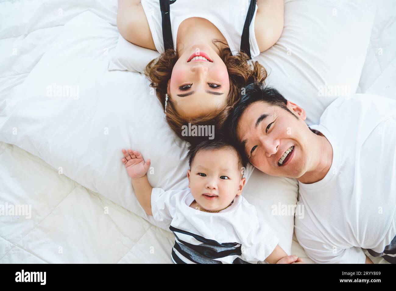 Top view of Asian family with father mother and son on white pillow bed ...
