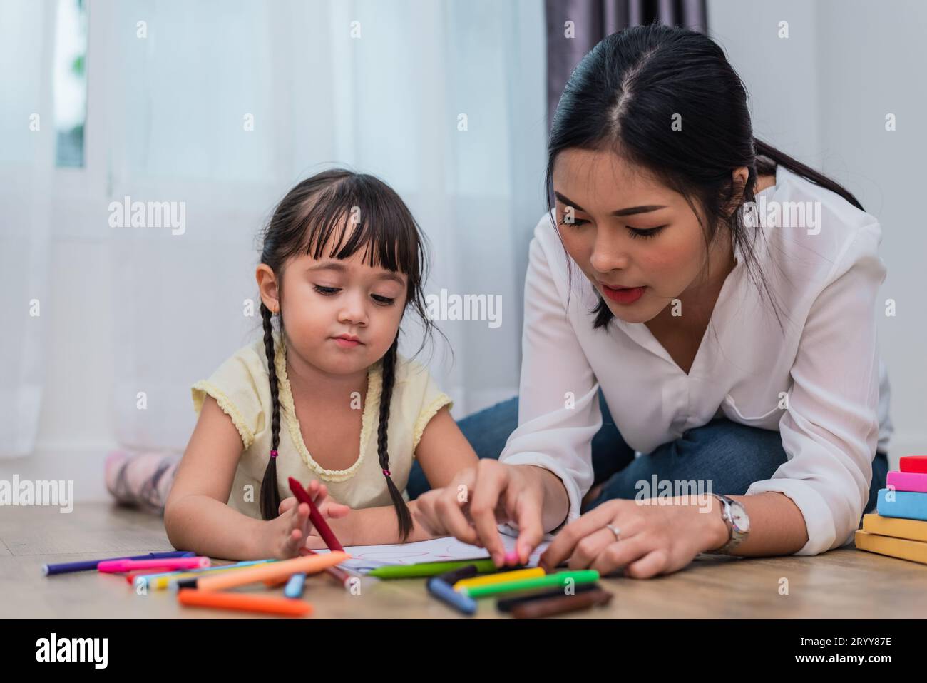 Mother teaching girl in drawing class. Daughter painting with colorful ...