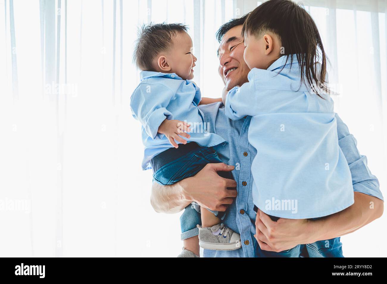 Happy father carrying two children in bedroom at home. Asian family ...