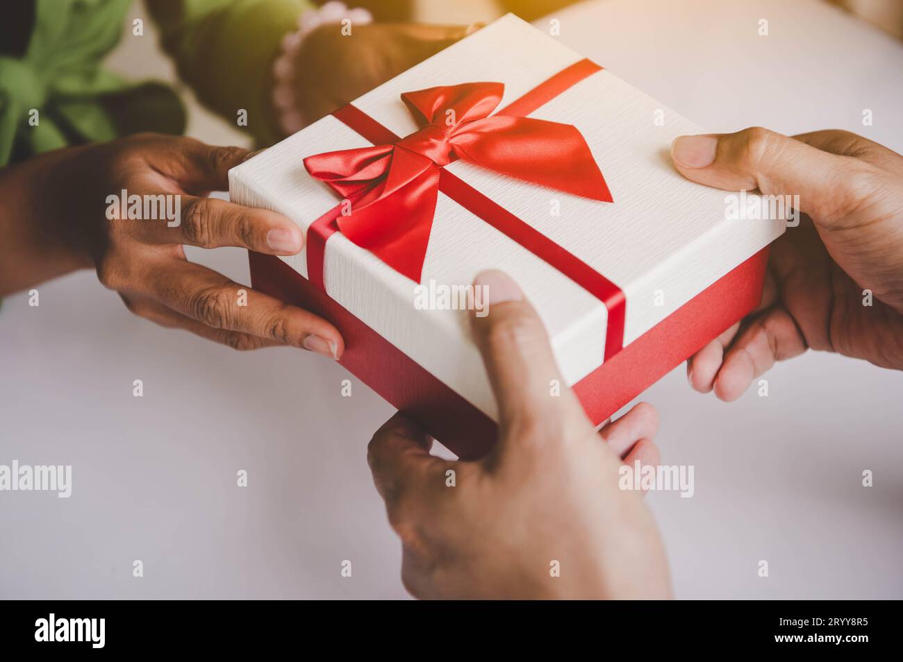 Closeup of hands giving gift box with red ribbon in Christmas day and ...