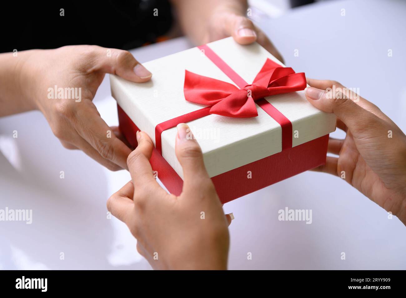 Closeup of hands giving gift box with red ribbon in Christmas day and ...