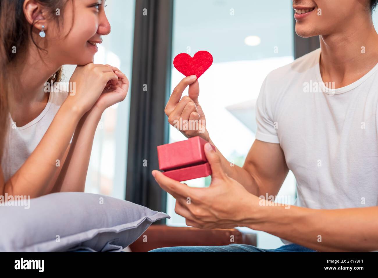 Man holding gift box for surprise girlfriend at their home. Woman ...