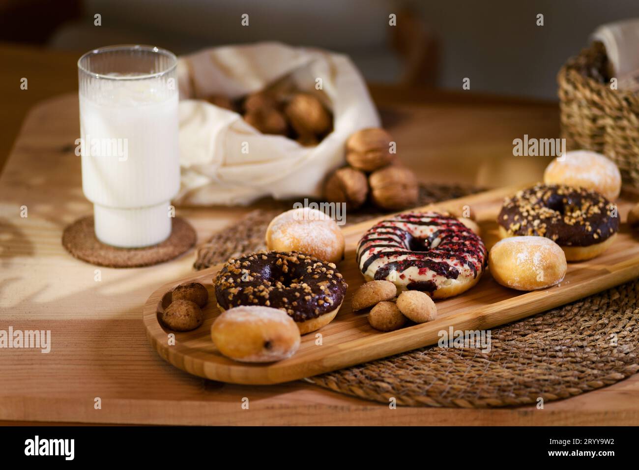On a wooden plate, three donuts, chocolate-stuffed cookies, and small ...