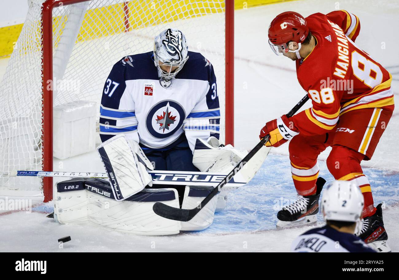 Winnipeg Jets goalie Connor Hellebuyck, left, blocks a shot by Calgary ...