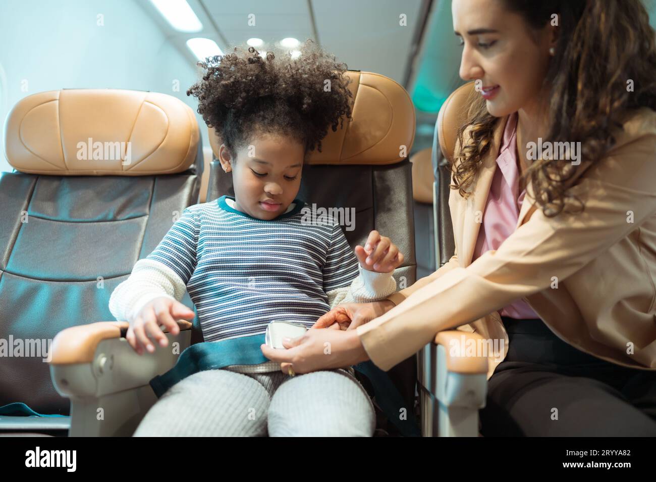 A mother assists her youngster in fastening his seatbelt to keep him ...