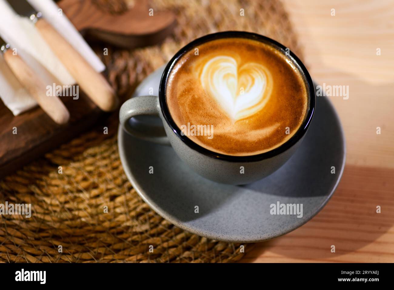 A close capture of a latte in a gray cup. Set upon a woven serving mat ...