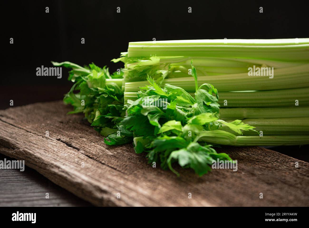Bunch of fresh celery stalk on wooden table with leaves on black ...