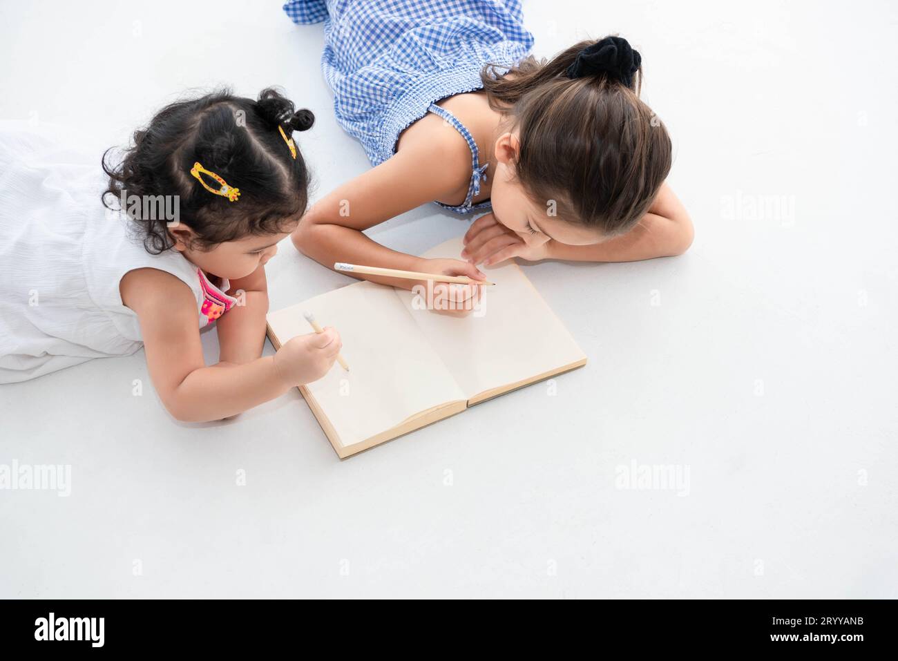 Top view of happy two sister drawing in sketch book together at home or ...