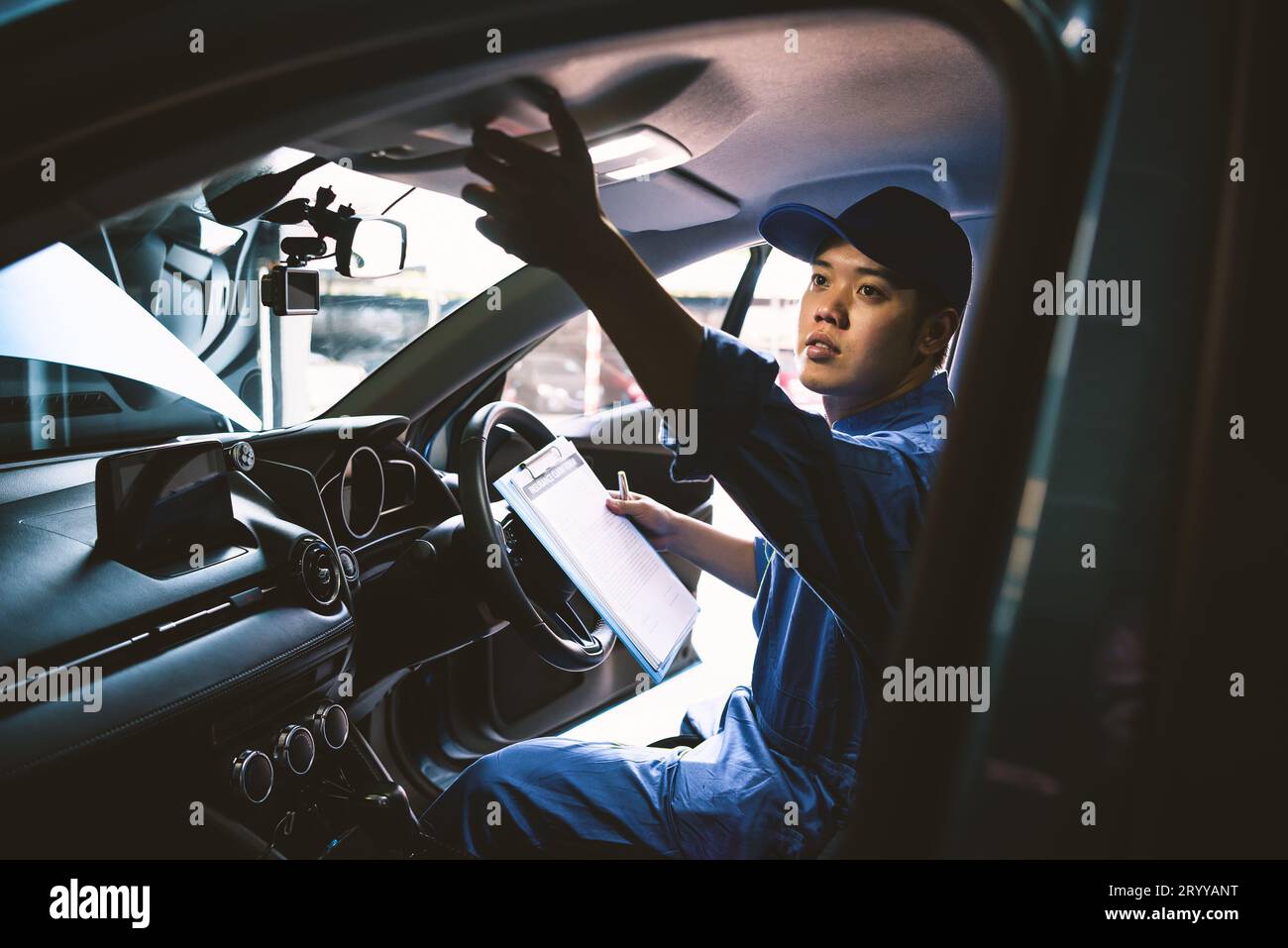 Mechanic holding clipboard and checking inside car to maintenance ...